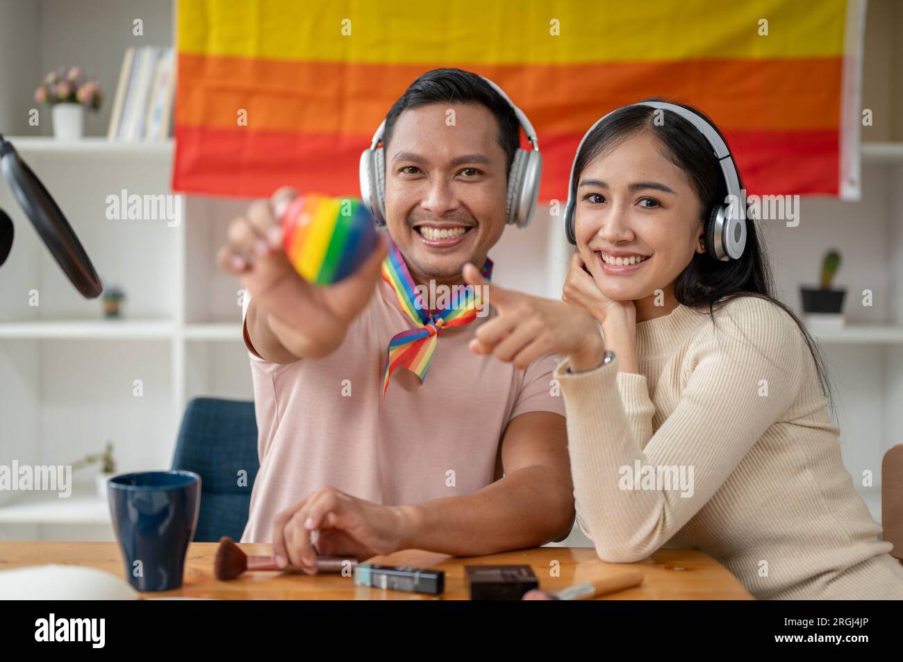 An attractive and happy Asian gay man in headphones holding the LGBT ...