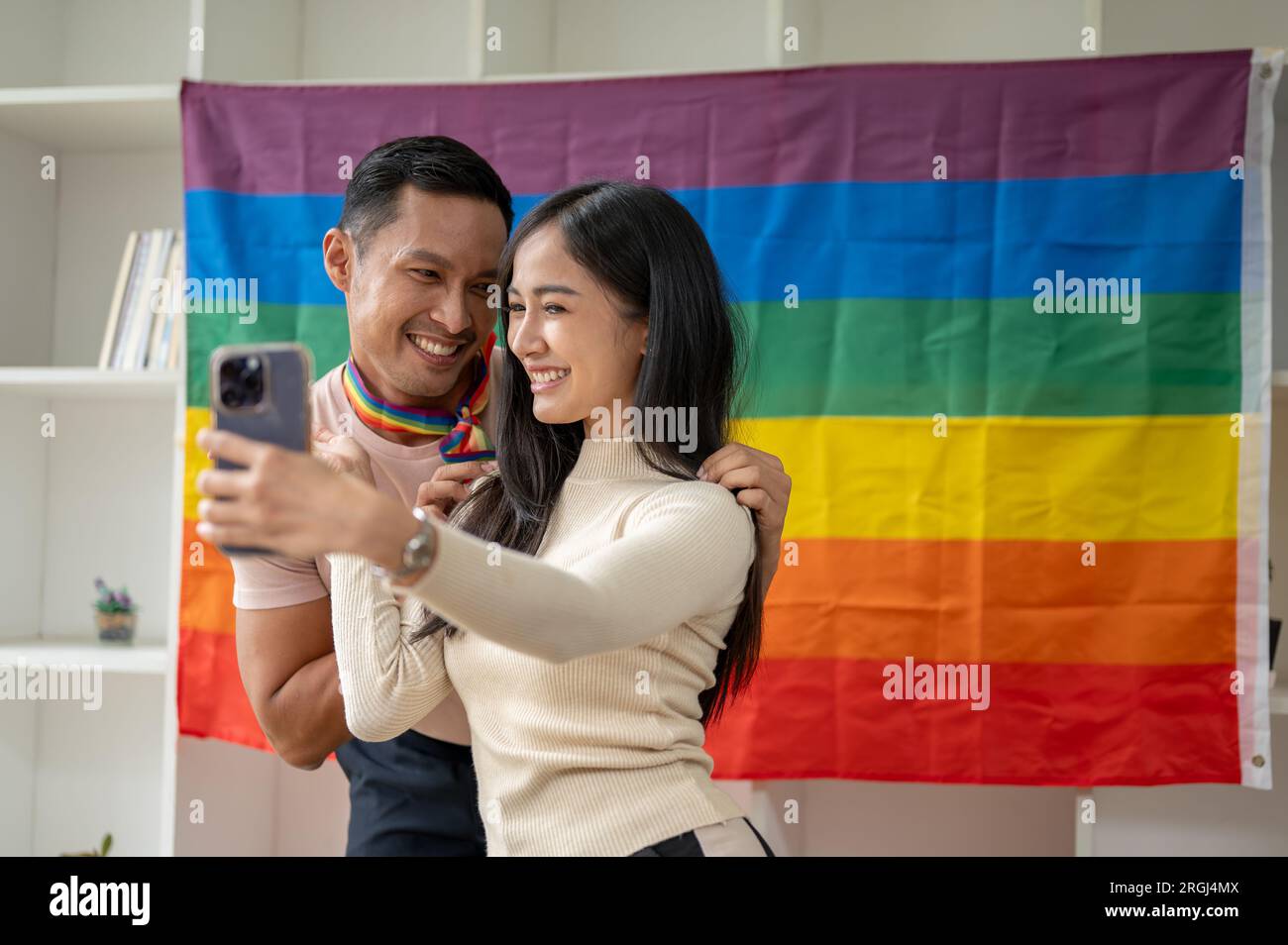 An attractive Asian girl is taking selfies or recording vlog with her gay friend in a living ...