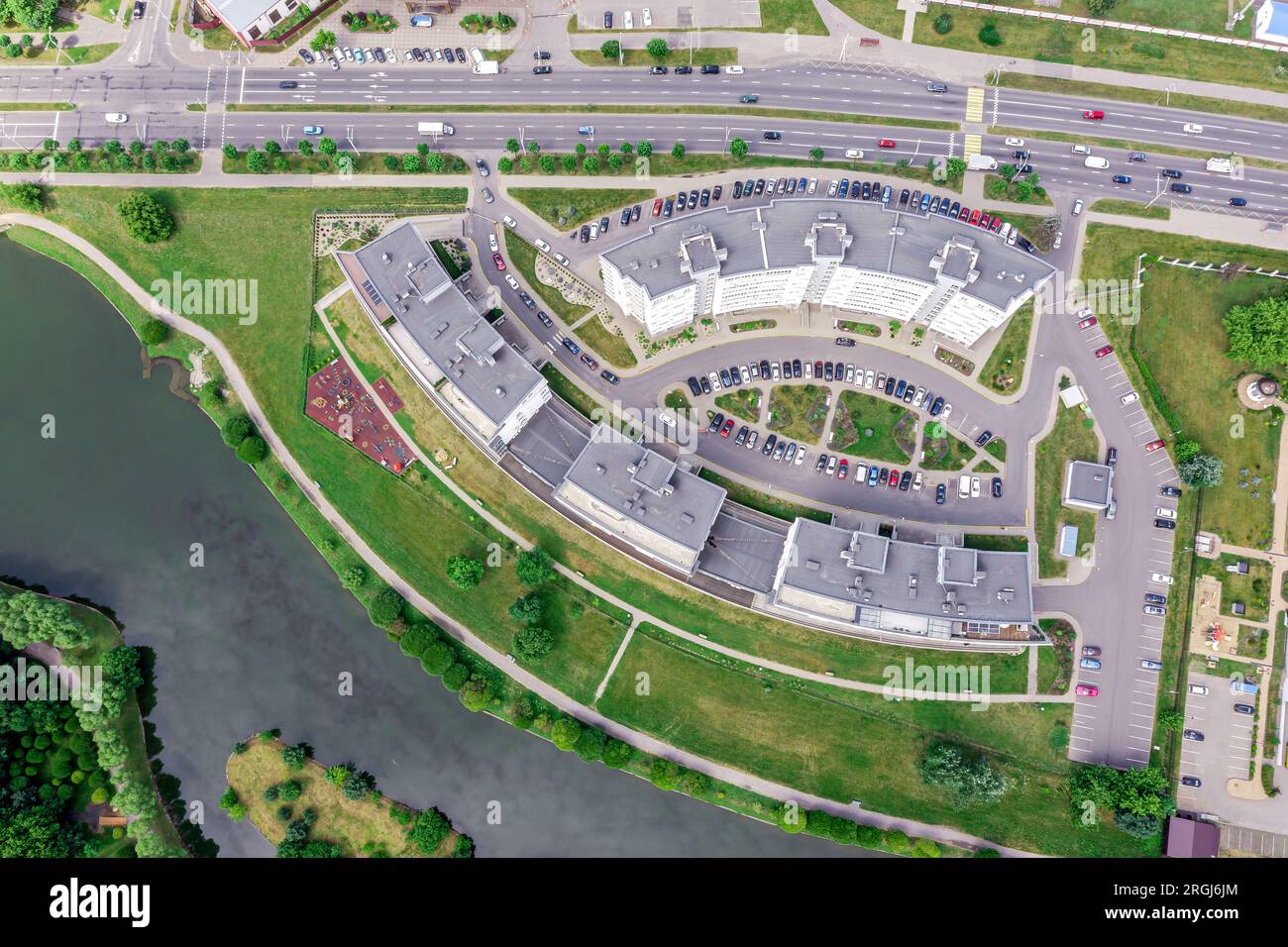 apartment buildings on riverbank and driveway with car traffic. summer ...