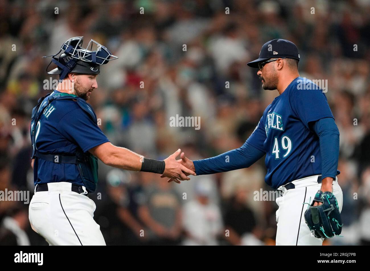 Seattle Mariners' Cal Raleigh, left, greets relief pitcher Isaiah ...