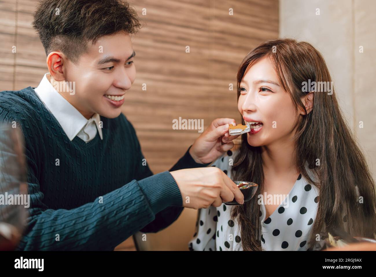 Young Asian Man Feeding Happy Girlfriend With Tasty Food In Restaurant