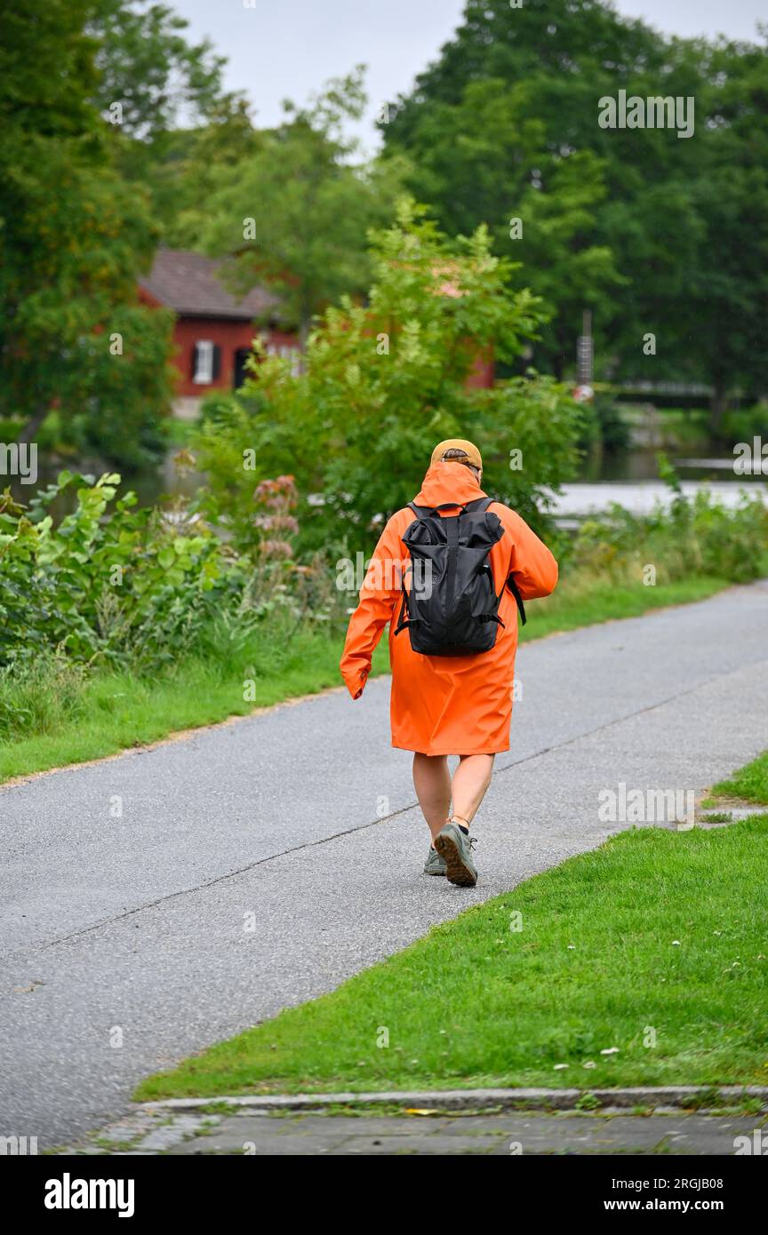 Person walking in a orange raincoat near Black river Orebro Sweden ...