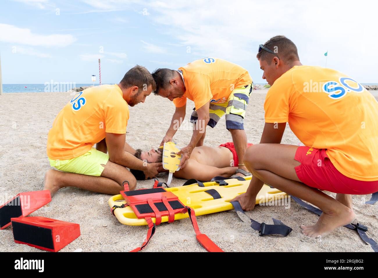 Lifeguards preparing a injured man to move him with a stretcher on a ...