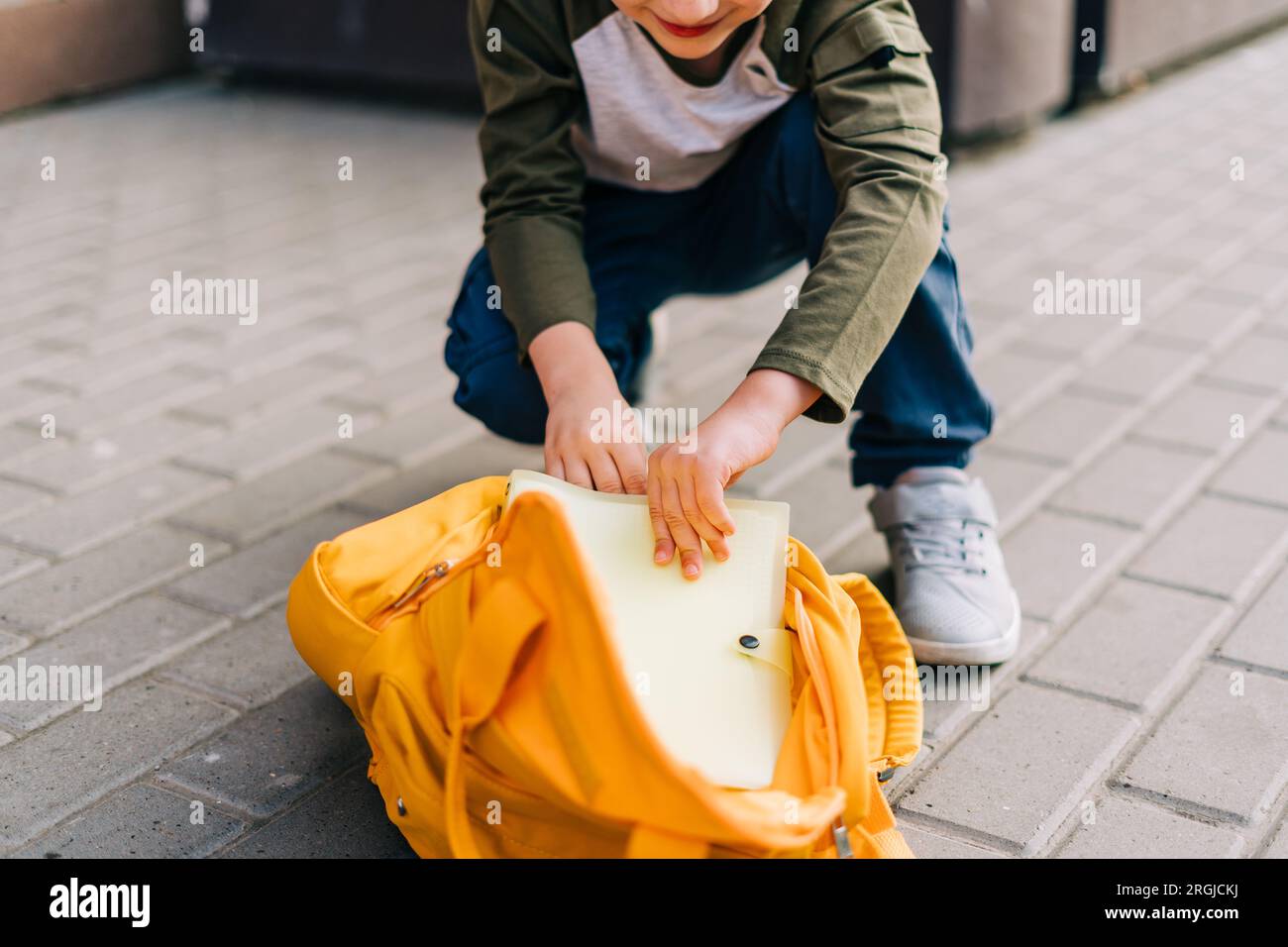 Back to school. Cute child packing backpack, holding notepad and ...