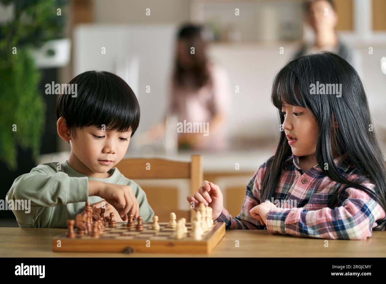 two asian children brother and sister sitting at table at home playing ...