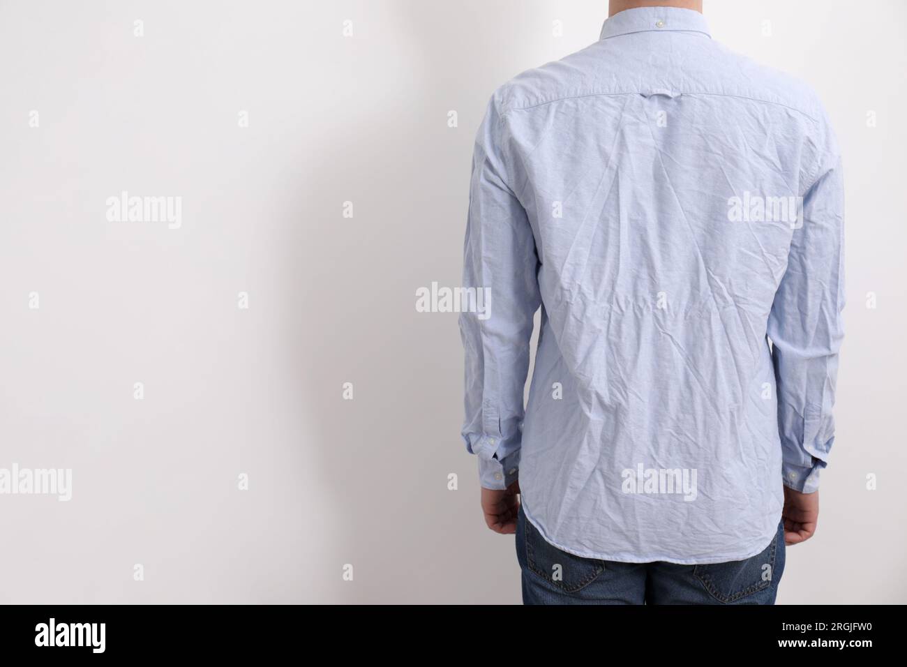 Man wearing rumpled shirt on white background, back view Stock Photo ...