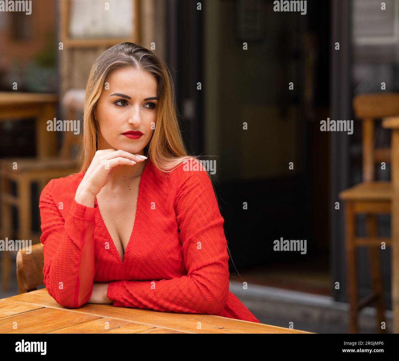 beautiful girl in a red dress at a table in a cafe Stock Photo - Alamy