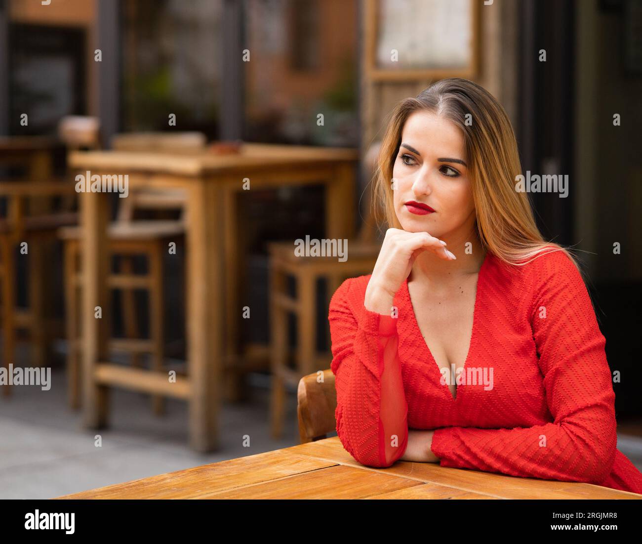beautiful girl in a red dress at a table in a cafe Stock Photo - Alamy