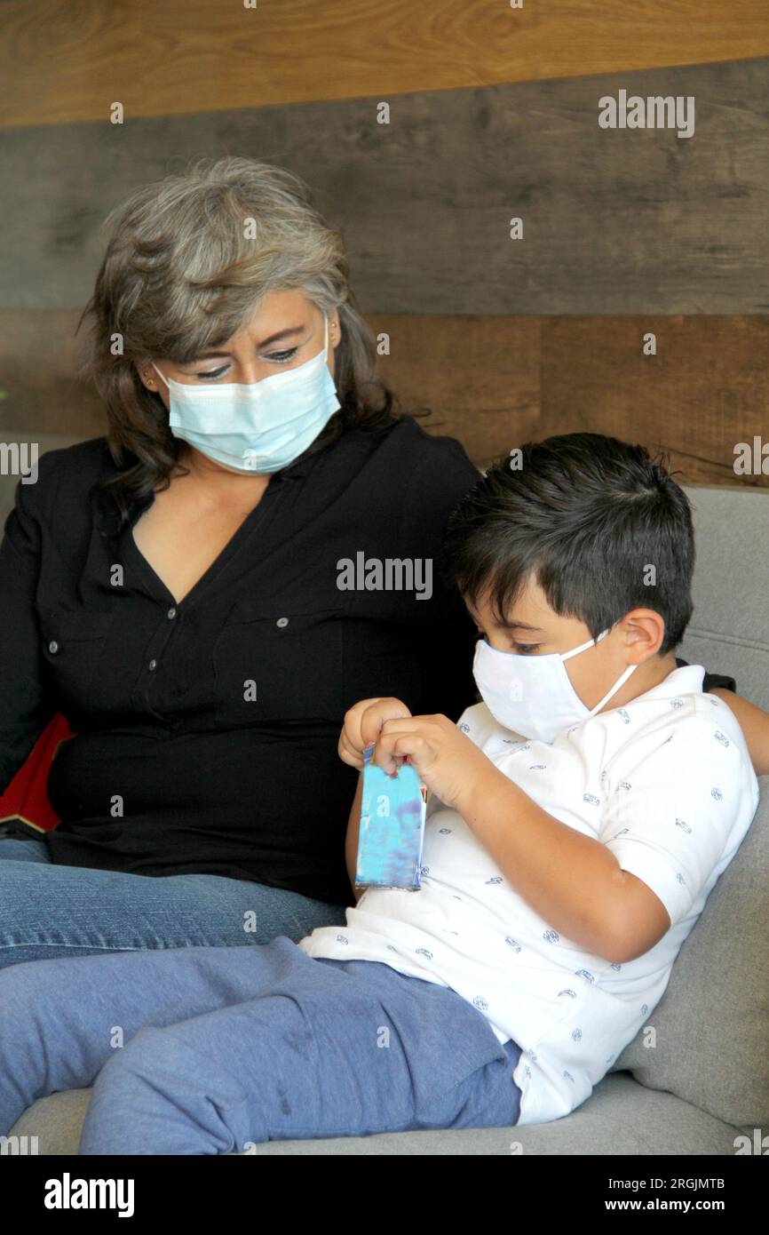 Latin woman, grandmother and child 7 years with protection mask ...