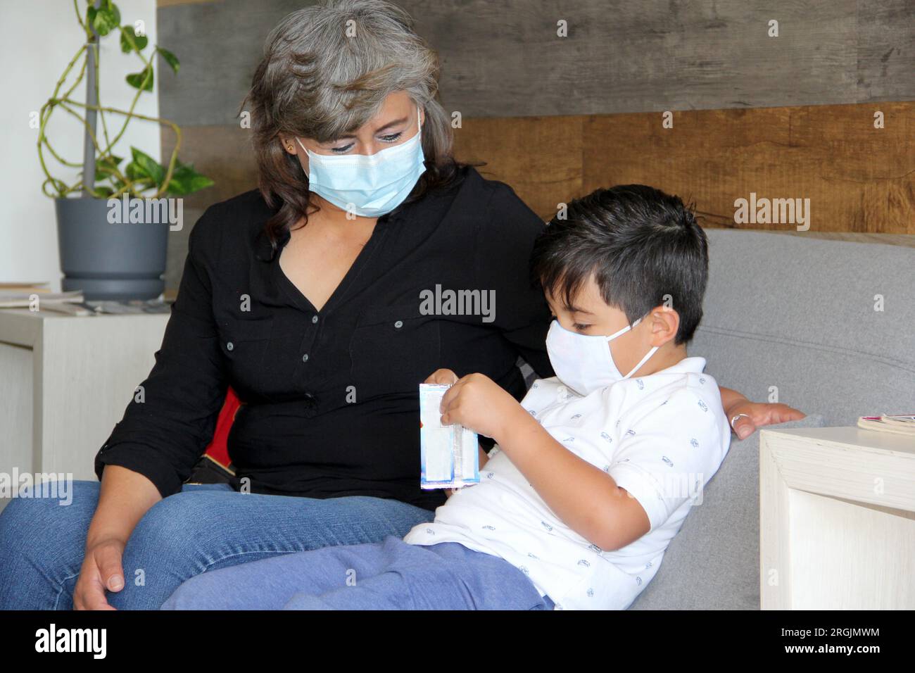 Latin woman, grandmother and child 7 years with protection mask ...