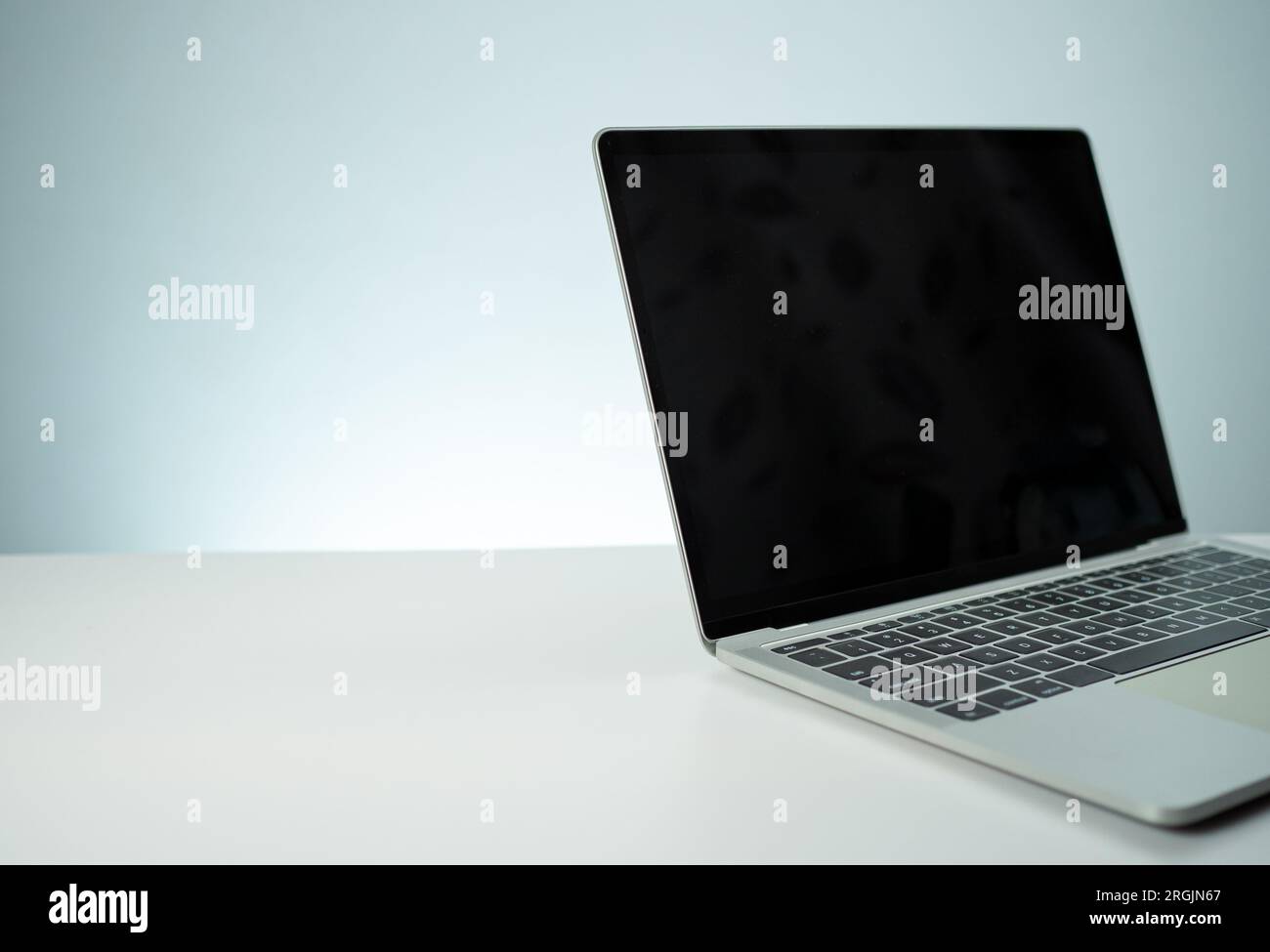 The computer image has a blank black screen. placed on a white table ...