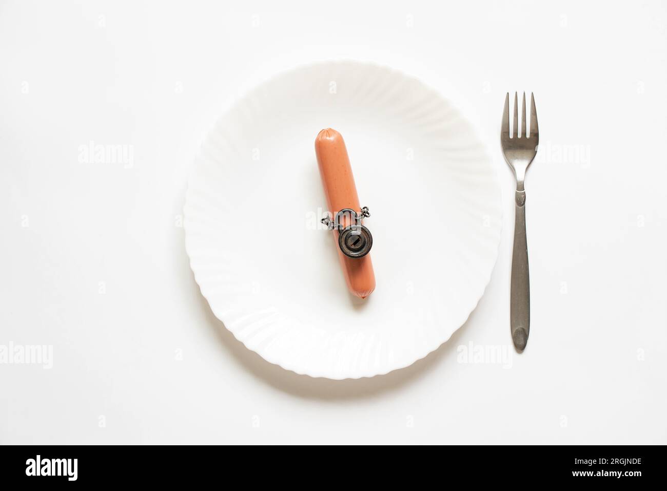 Sausage on a chain under a padlock on a plate and a fork next to it ...