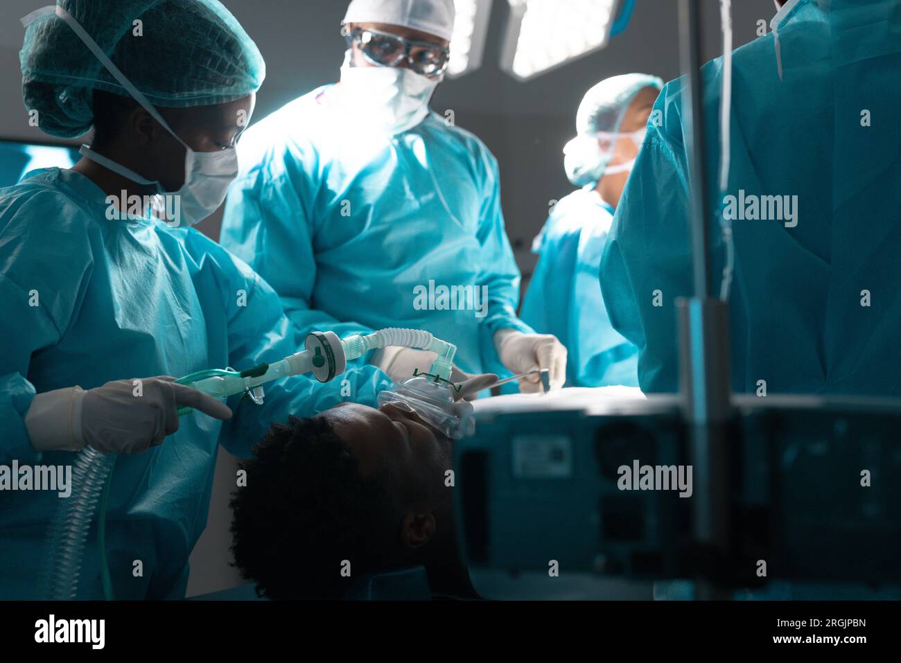Diverse surgeons wearing surgical gowns operating on patient in ...