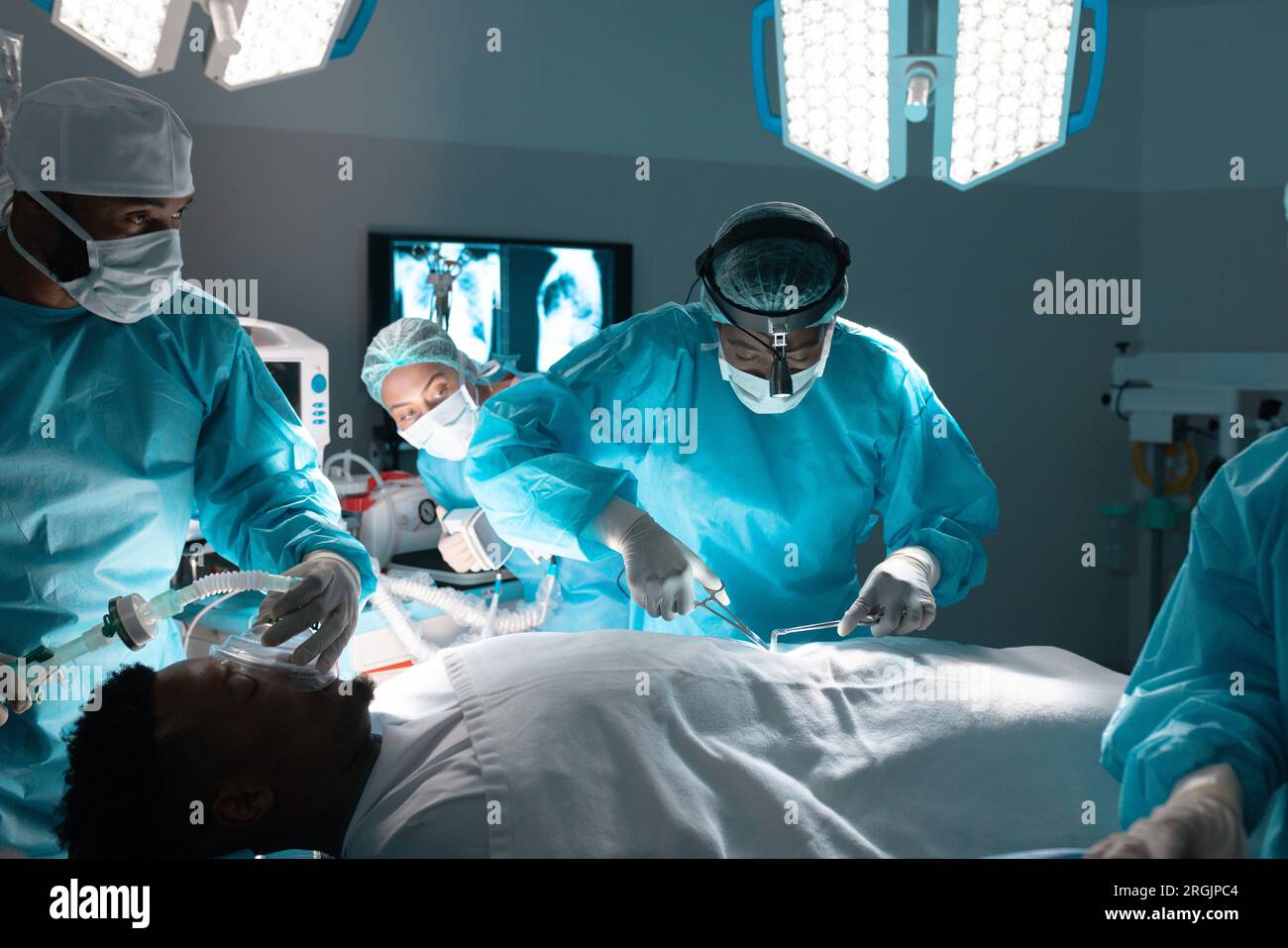 Diverse surgeons wearing surgical gowns operating on patient in ...