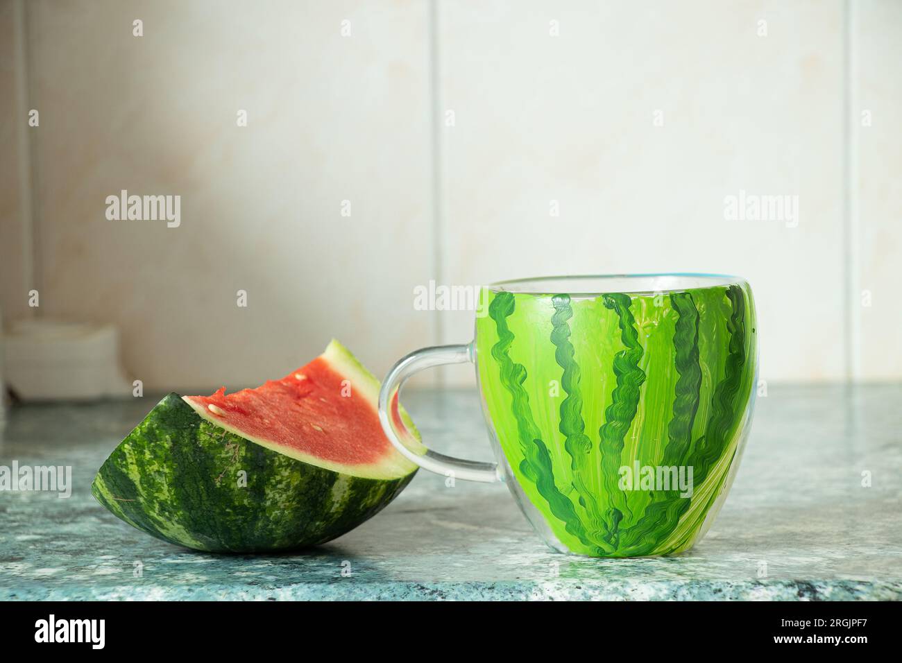A cup with a painted watermelon and a sliced watermelon next to it from ...