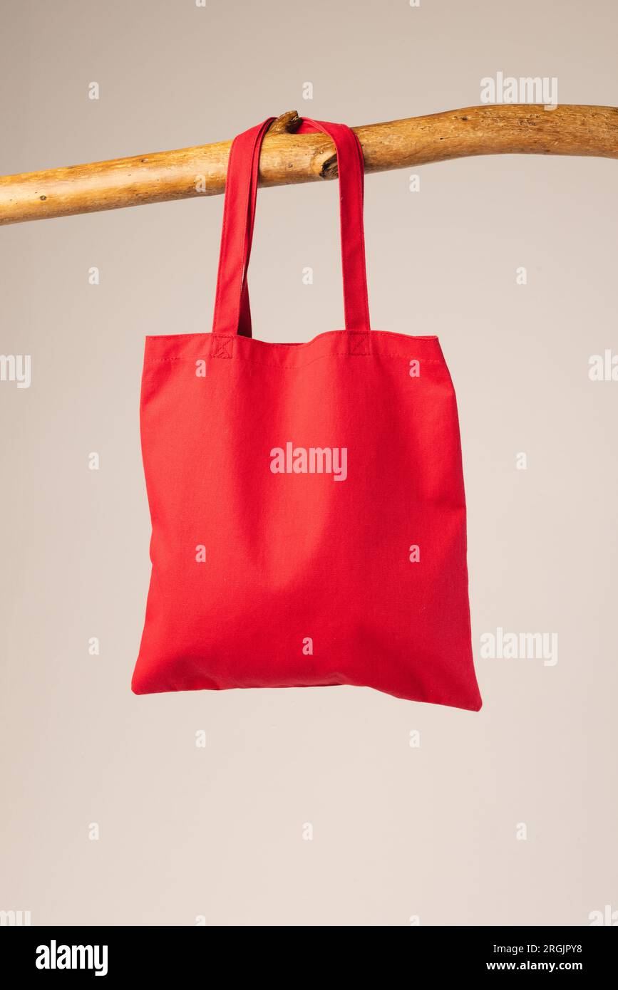 Red canvas bag hanging from wooden branch with copy space on white ...