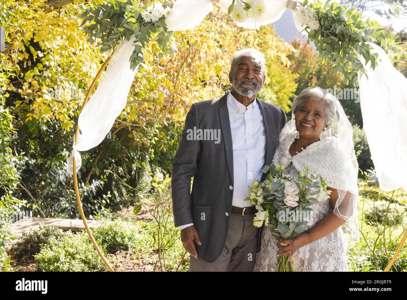 Portrait of happy senior biracial bride and groom at sunny outdoor ...