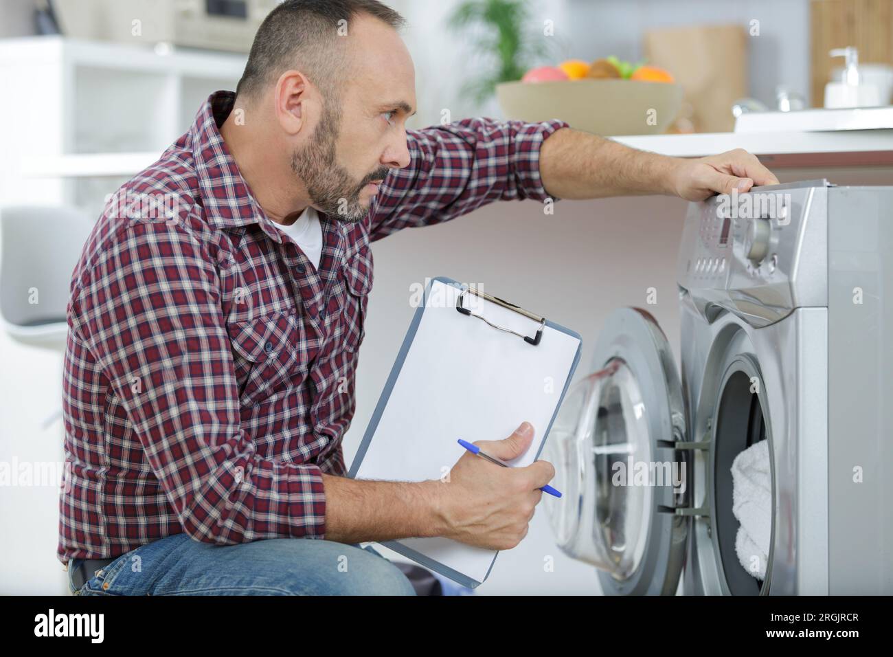 mature serviceman looking at washing machine Stock Photo - Alamy