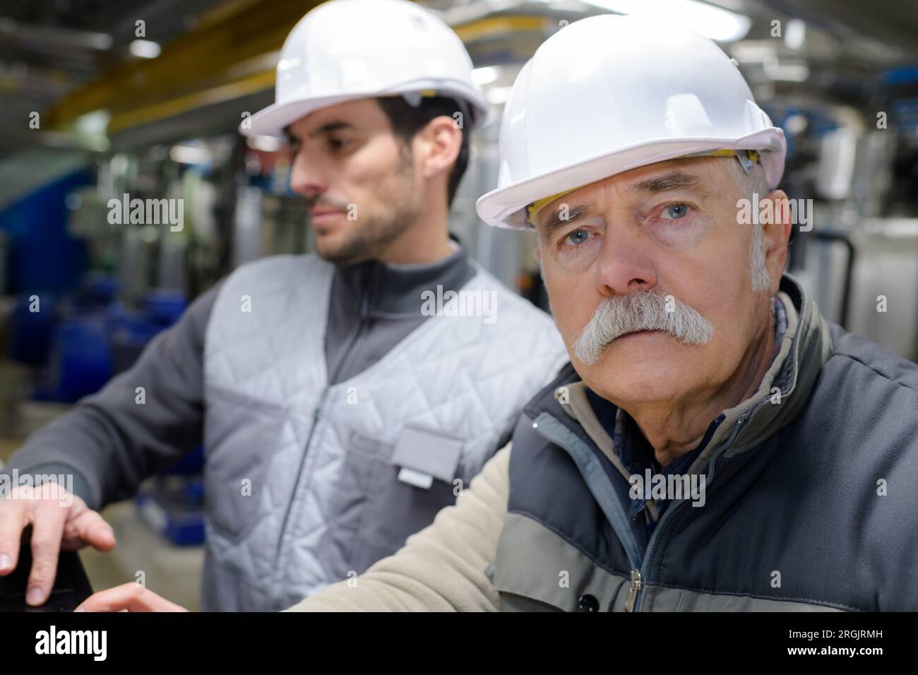 senior worker in safety vest and helmet coworker standing behind Stock ...