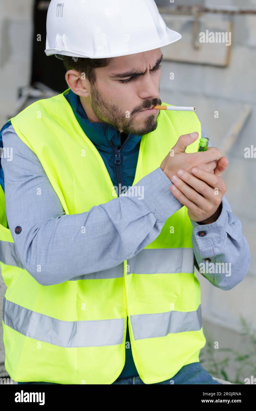 young builder smoking a cigarette on construction site Stock Photo - Alamy