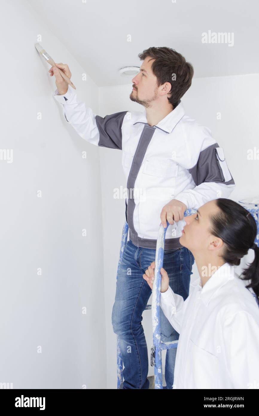 decorating team touching up the paint on an interior wall Stock Photo ...