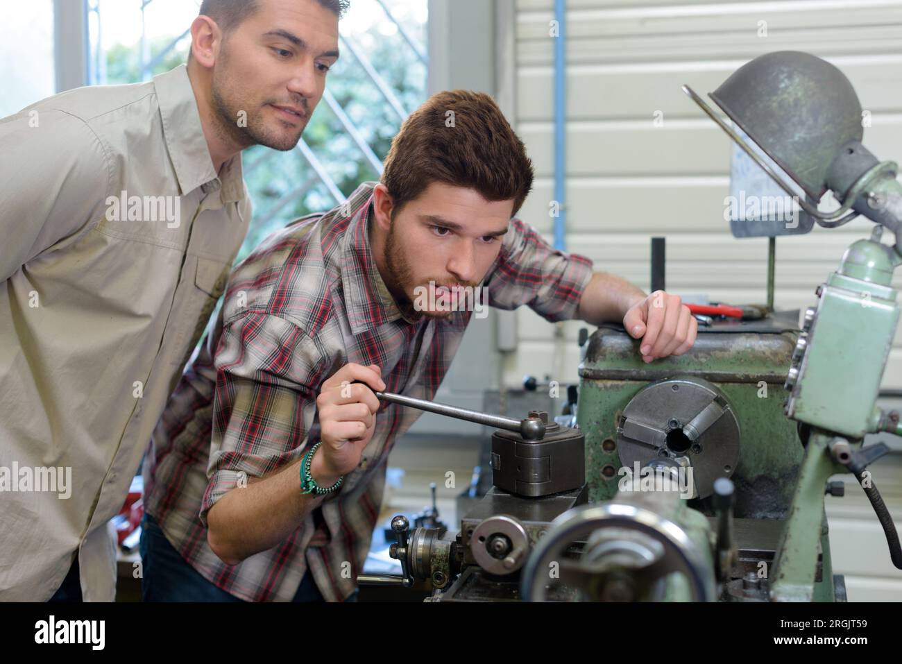 a portrait of workers watching bench drill Stock Photo - Alamy