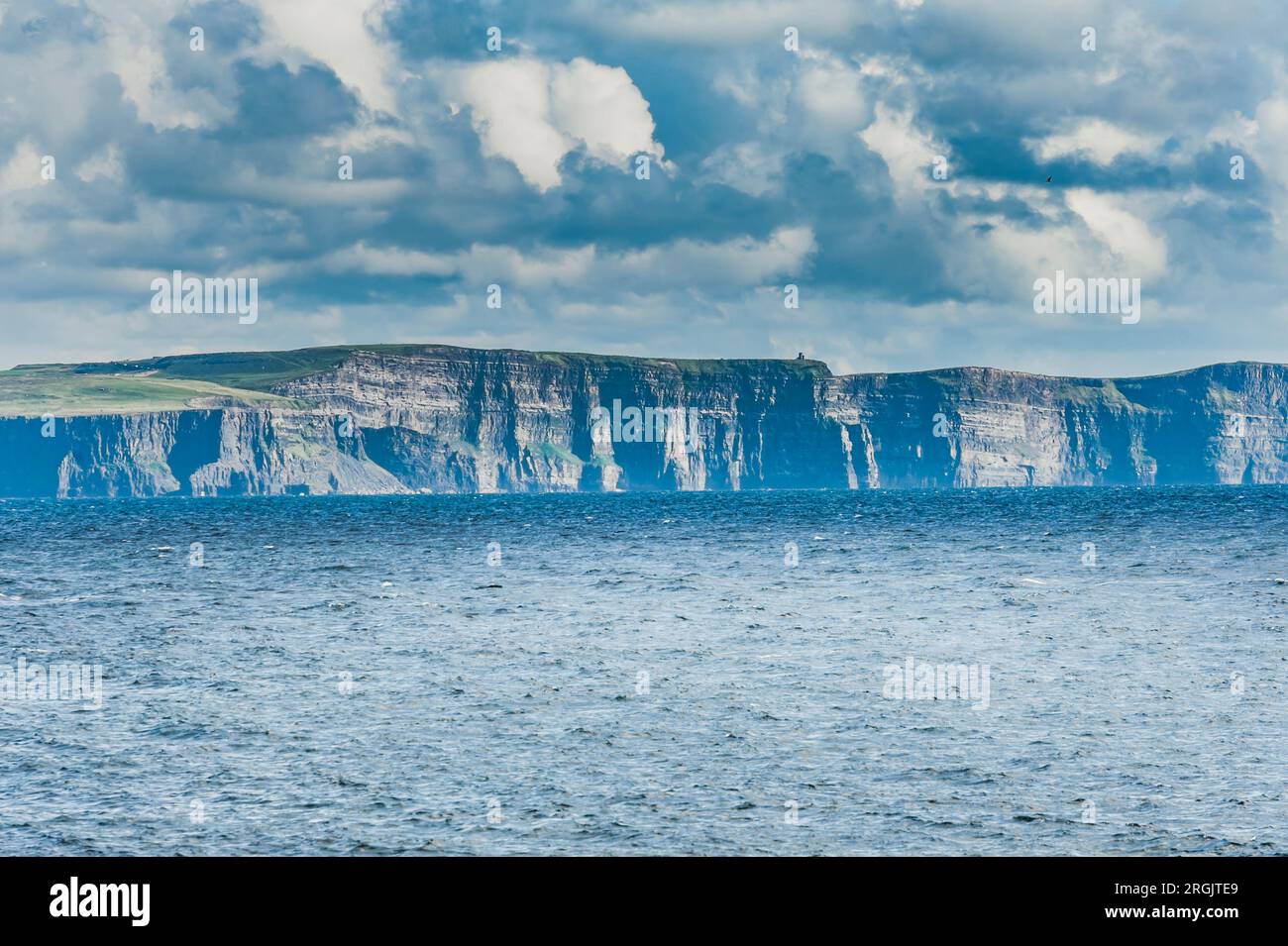 Cliffs of Moher front view from the sea. Big clouds hovering the high cliffs of Moher, west ...