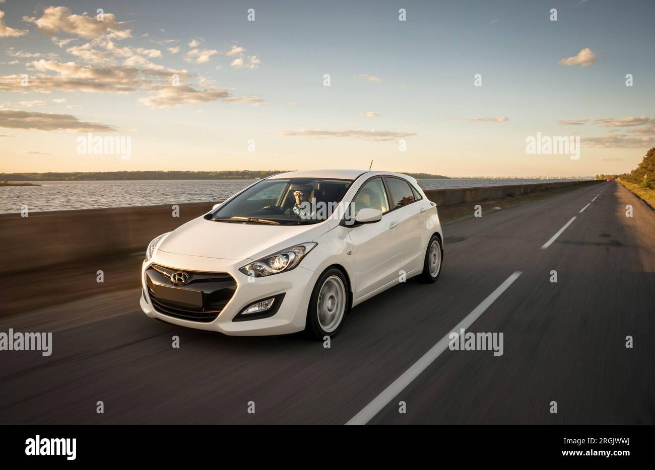 white Hyundai i30 driving along huge lake. Motion shot of korean ...