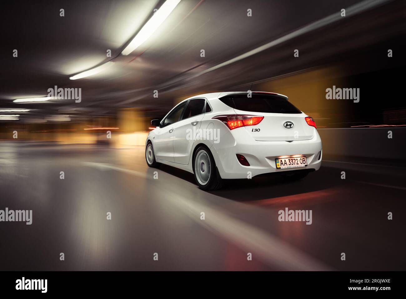 white Hyundai i30 driving inside parking garage. Motion shot of korean ...