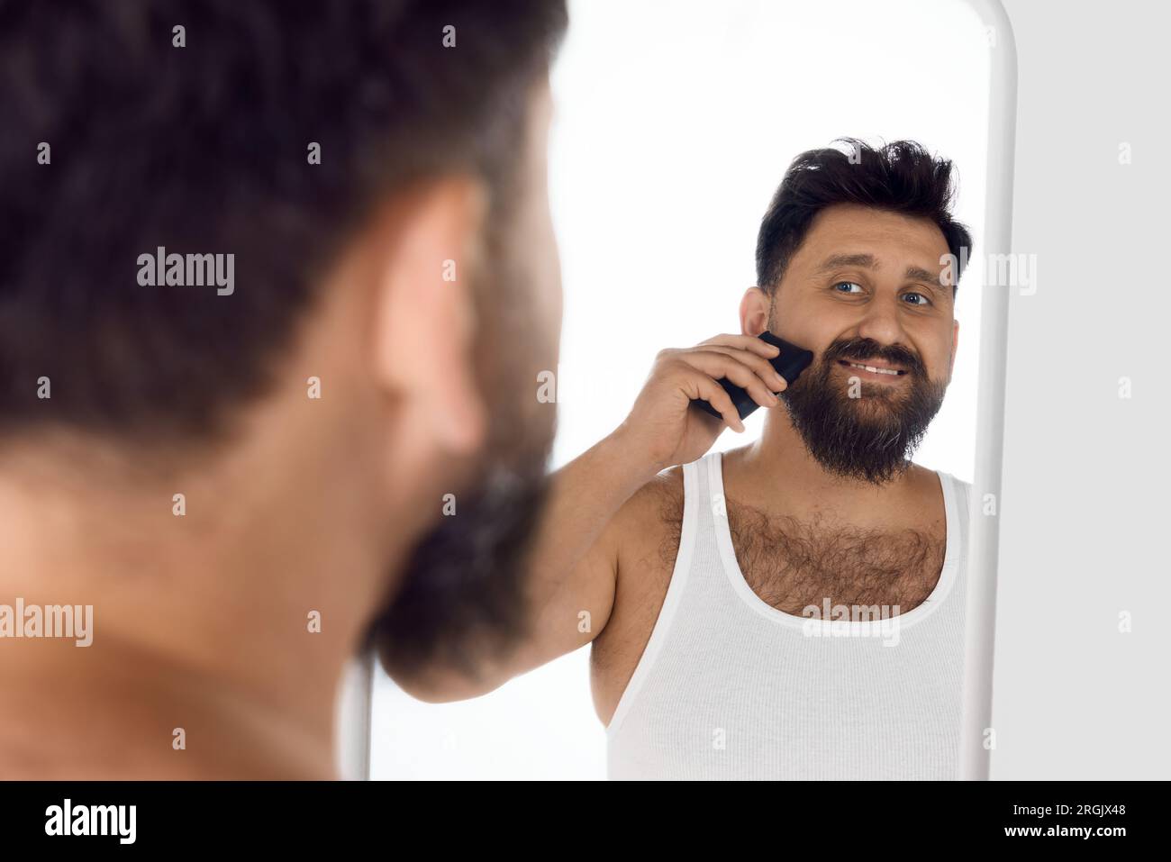 Mature, smiling man looking in mirror, taking care after beard, shaving ...