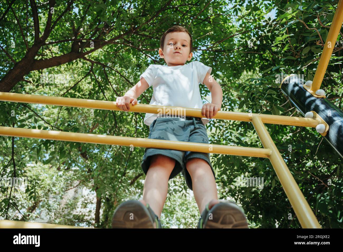 child boy playing and climbing on horizontal bars on the playground in ...
