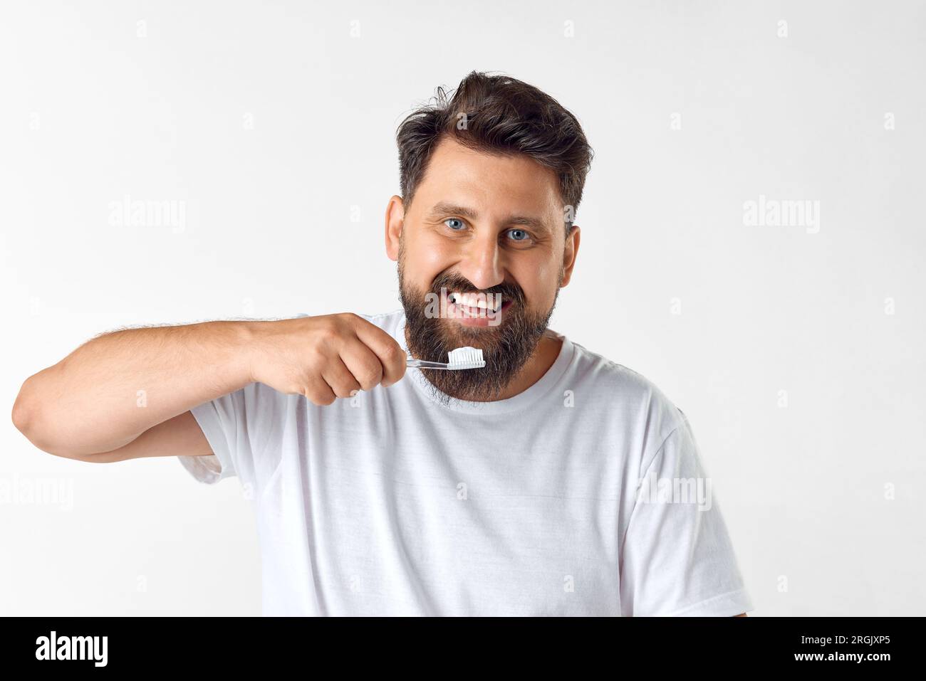 Perfect smile. Bearded mature man brushing teeth against white studio background. Dental hygiene ...