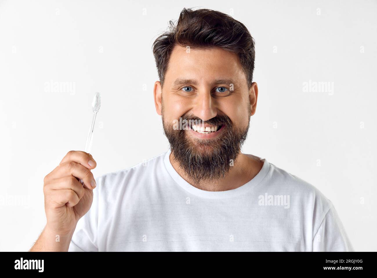 Perfect smile. Bearded mature man holding toothbrush against white studio background. Dental ...