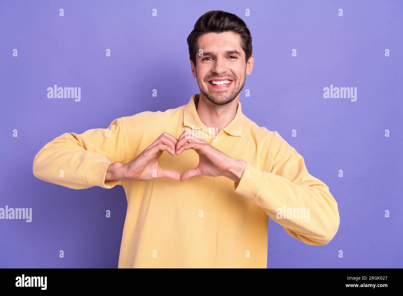 Photo of cheerful charming guy wear yellow shirt showing arms heart ...