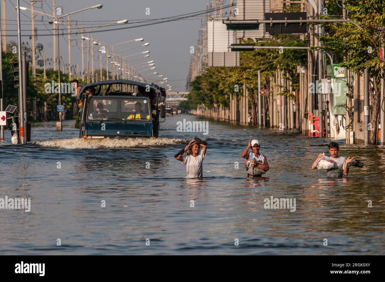 Thai flood refugees wade through dangerous floodwaters on Phahon Yothin ...