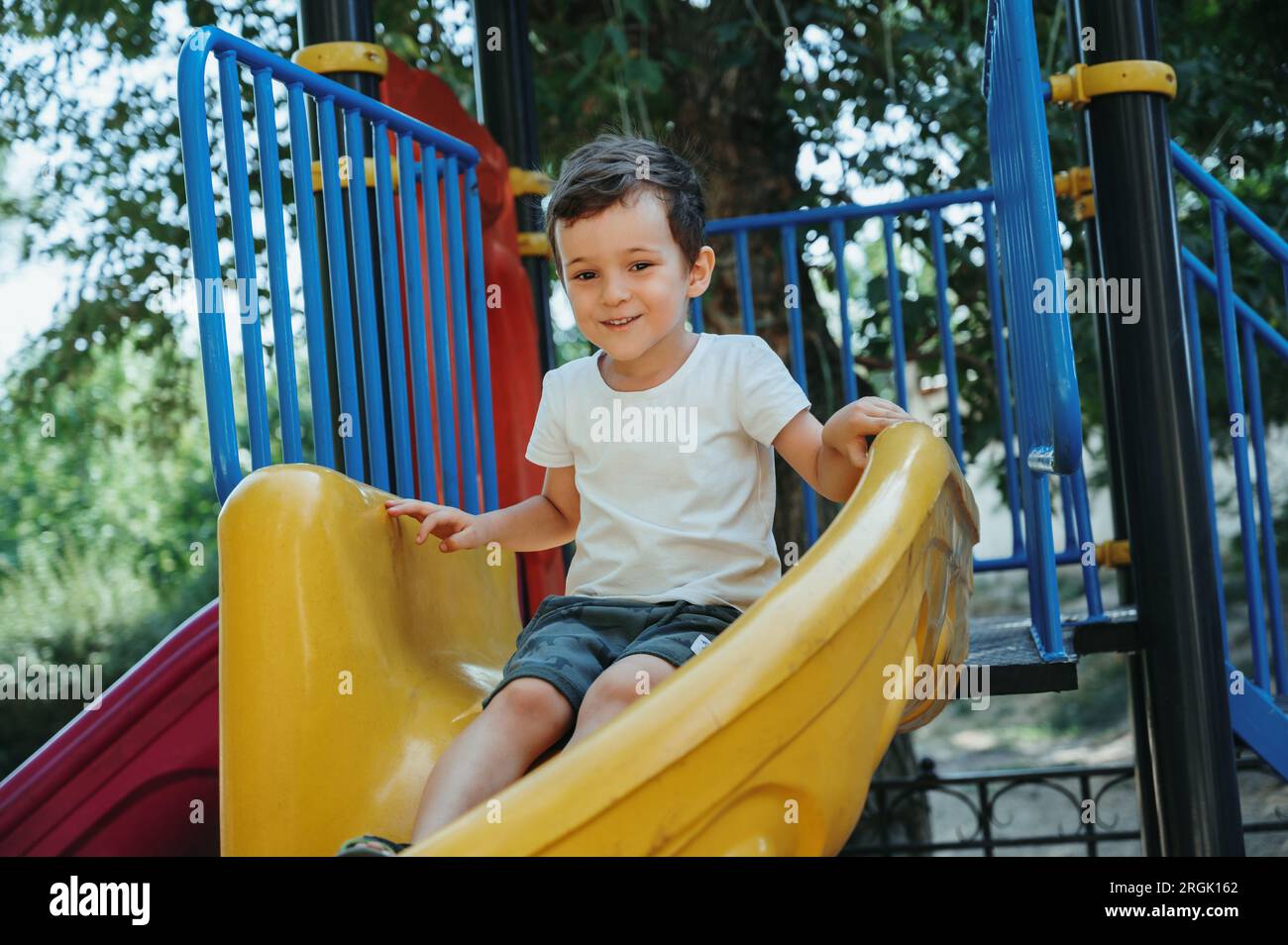 happy boy rides a slide on the playground in summer Stock Photo - Alamy