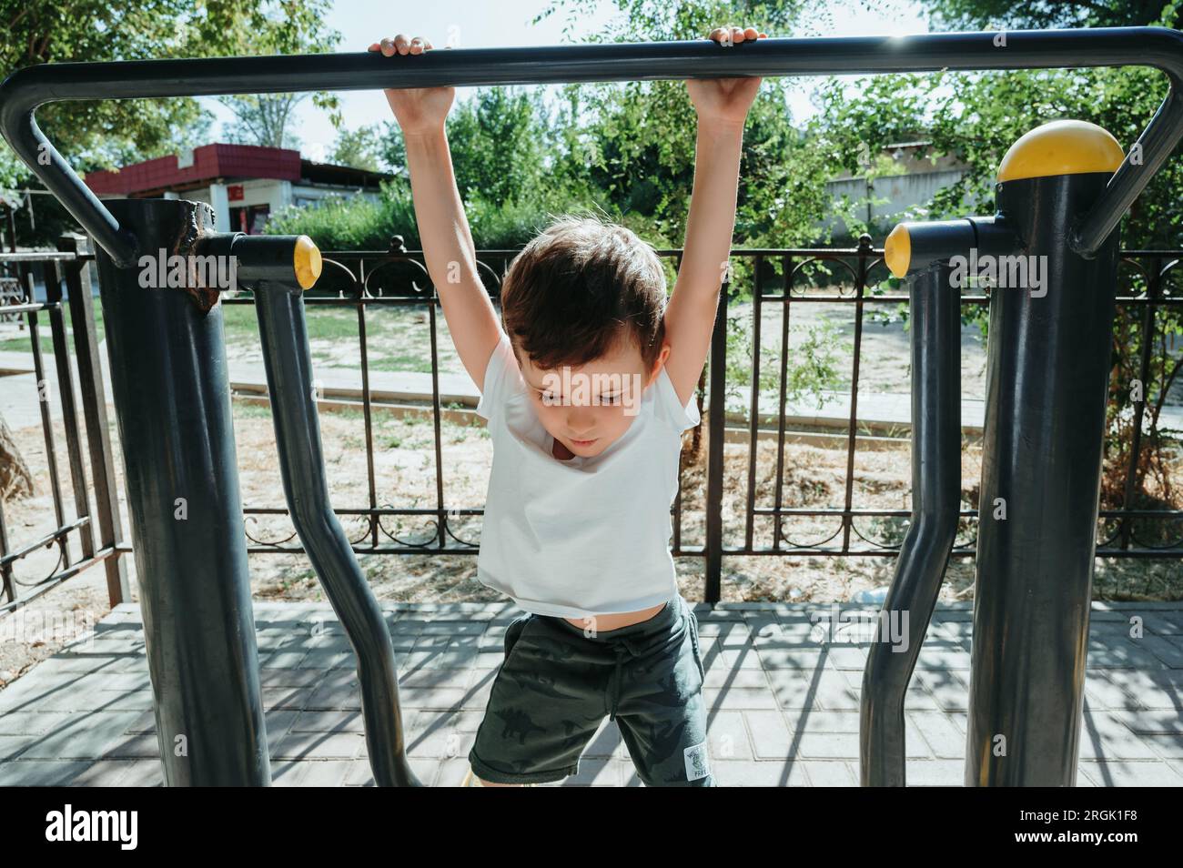 child boy playing and climbing on horizontal bars on the playground in ...