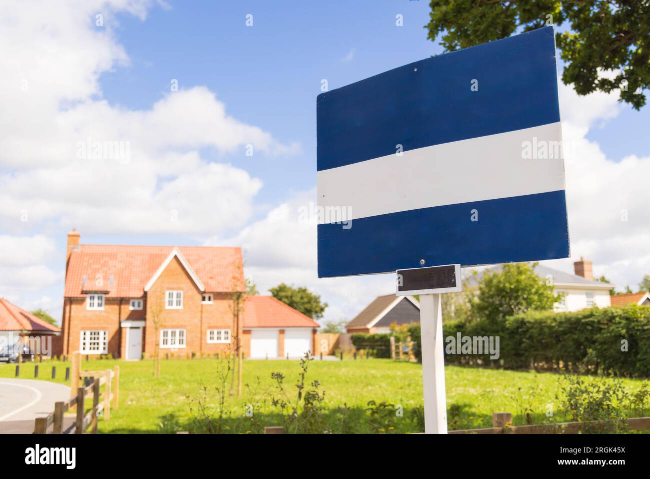 Blank estate agent for sale sign, with a house out of focus in the ...