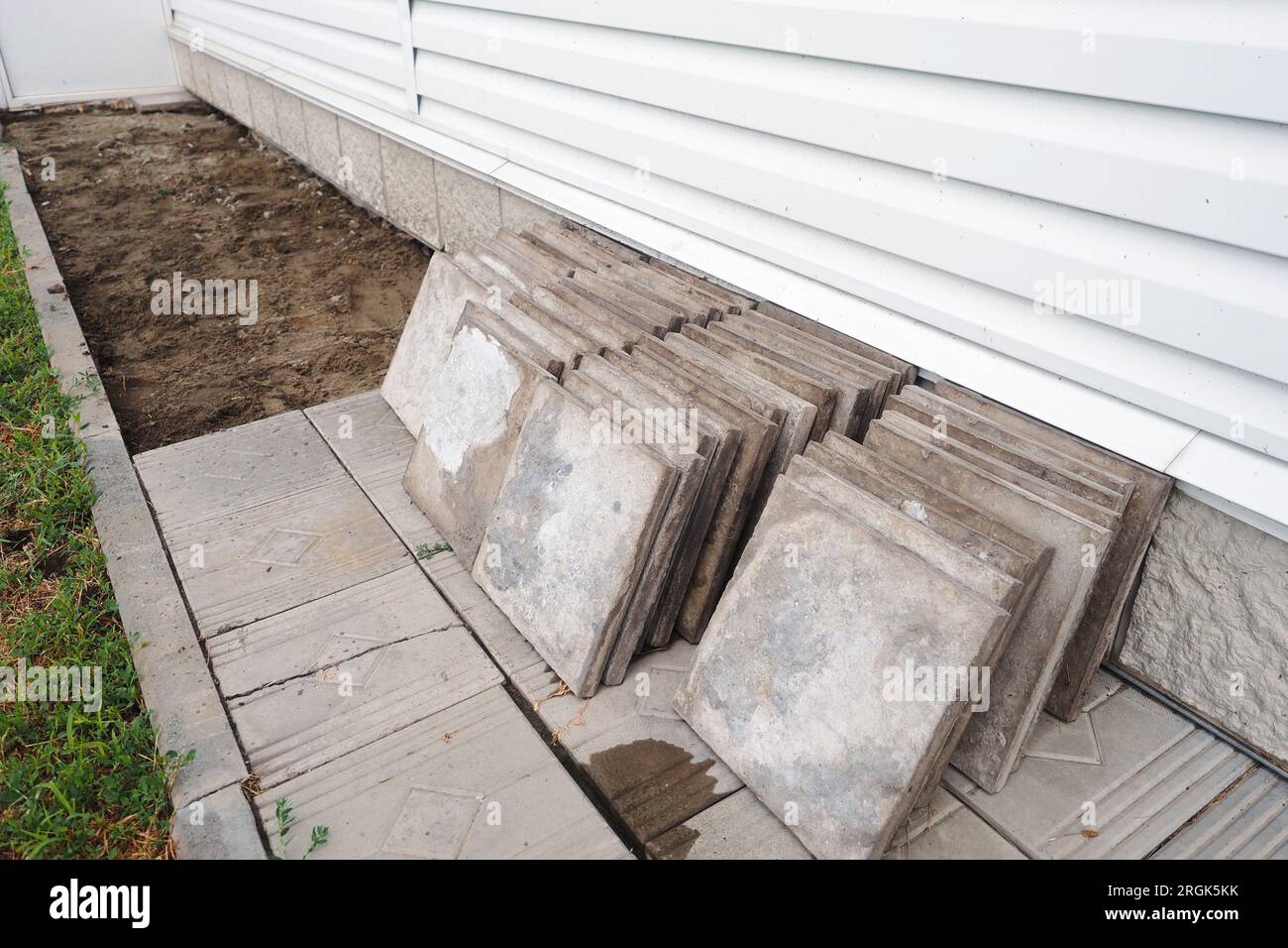 Facing concrete tiles lie on ground in stack. Replacing building ...