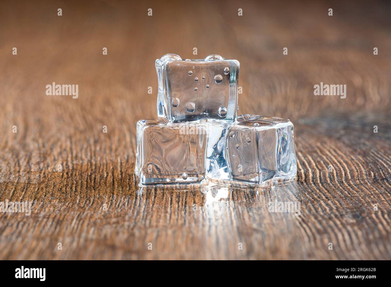 Several melted ice cubes on a wooden background. Drops of water on ice ...