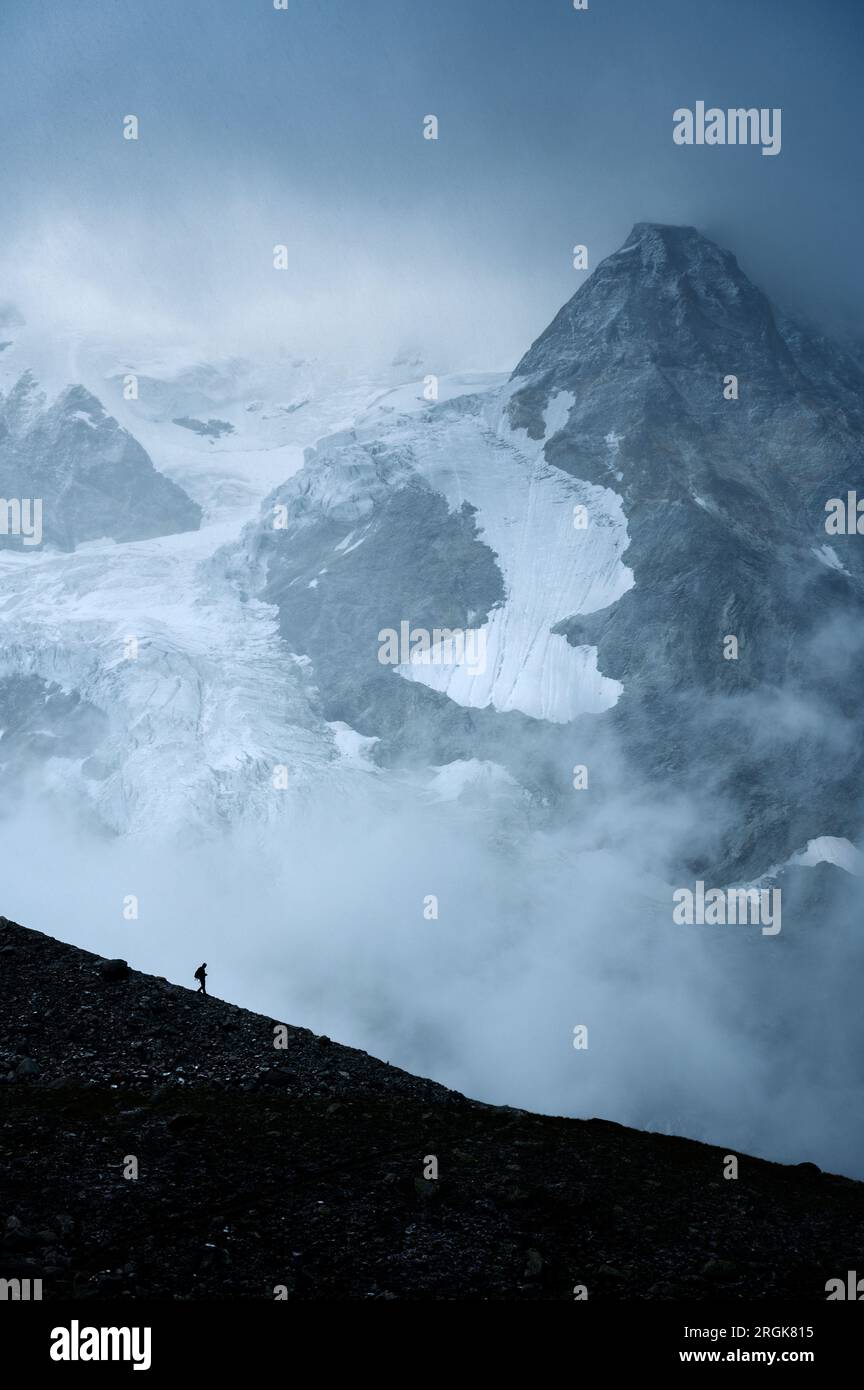 silhouette of a hiker in front of glaciers and alpine peaks in Val d ...
