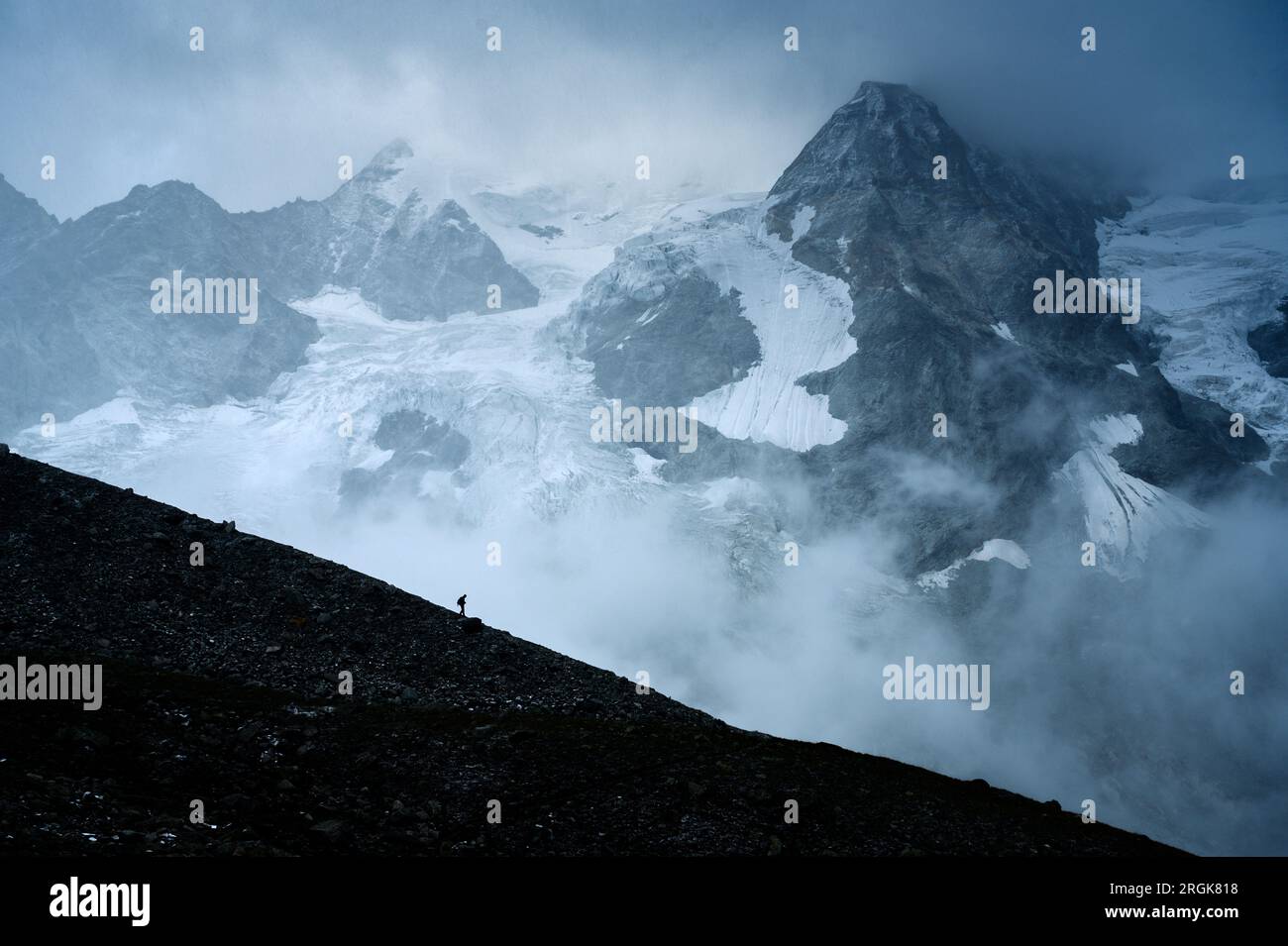 silhouette of a hiker in front of glaciers and alpine peaks in Val d ...