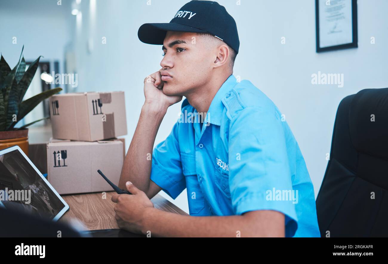 Safety, surveillance and a bored man security guard sitting at a desk ...