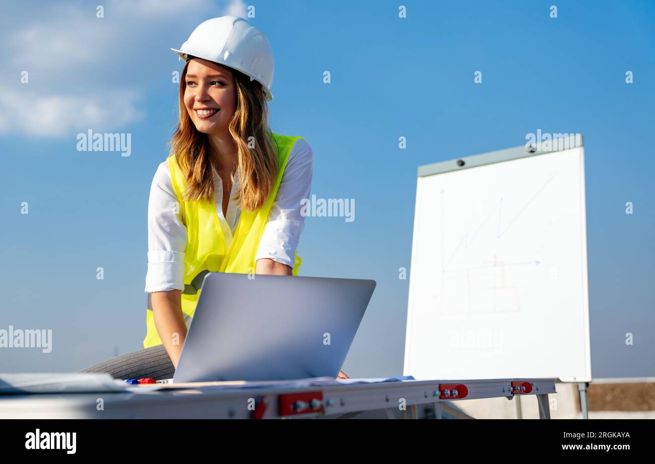 Young female construction specialist engineer reviewing blueprints at construction site Stock ...