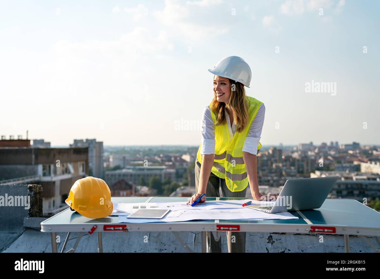 Young female construction specialist engineer reviewing blueprints at construction site Stock ...