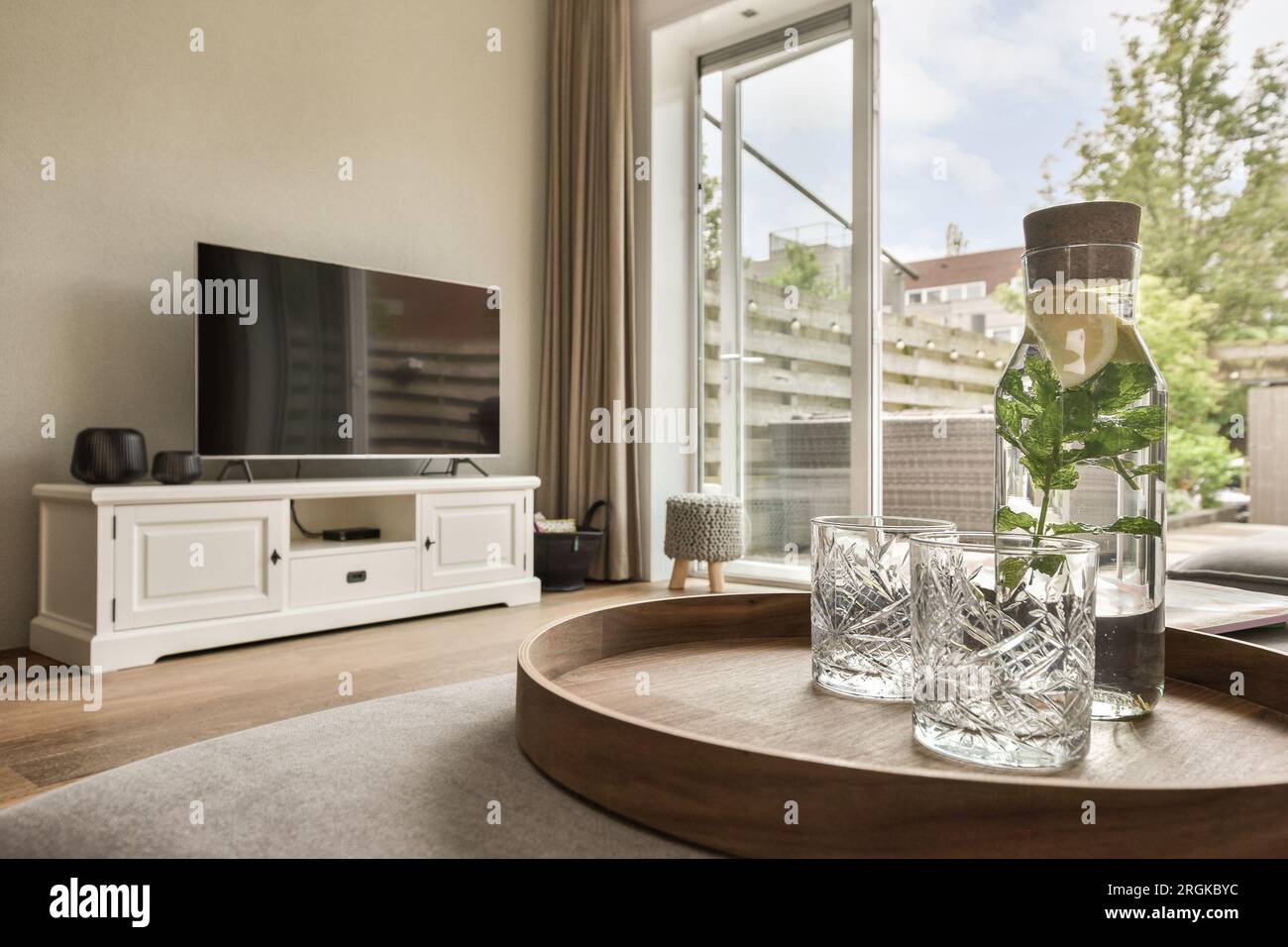 a living room with a glass vase on the coffee table and a television ...