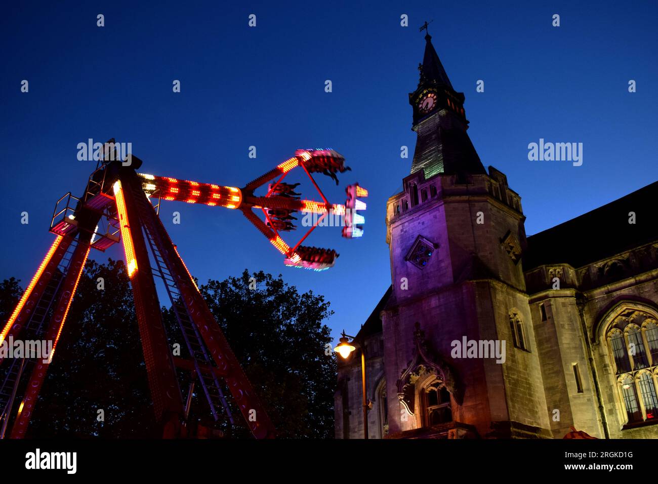 An illuminated fairground ride with Banbury Town Hall in the background ...