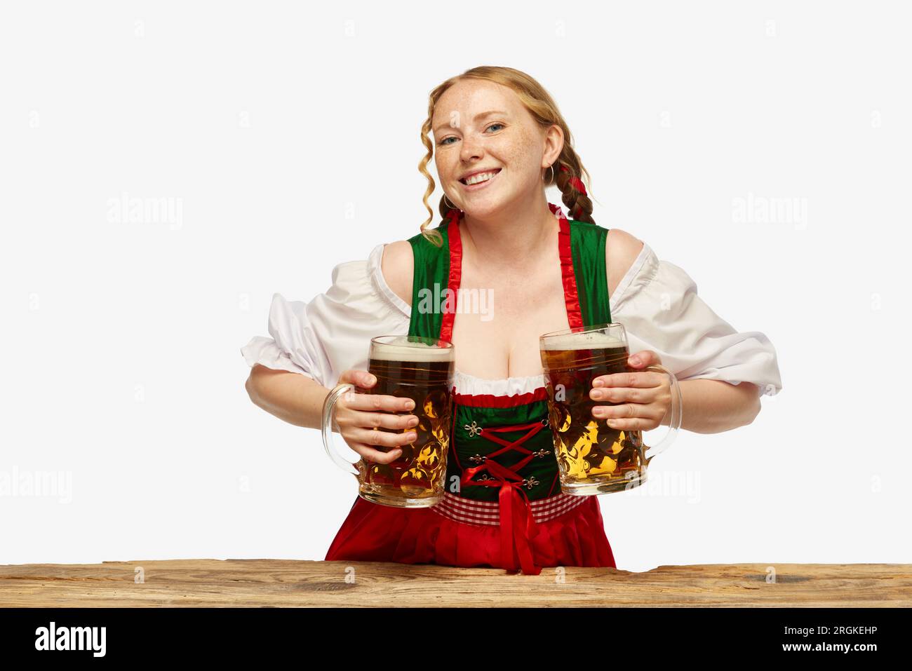Friendly young woman wearing folk German dirndl with two beer mugs over ...