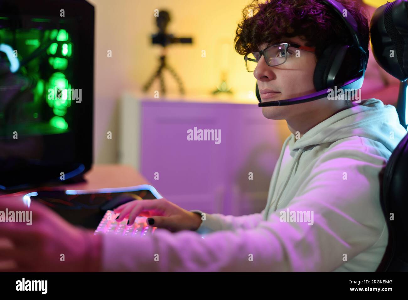 Side view of concentrated young male gamer in eyeglasses headphones ...