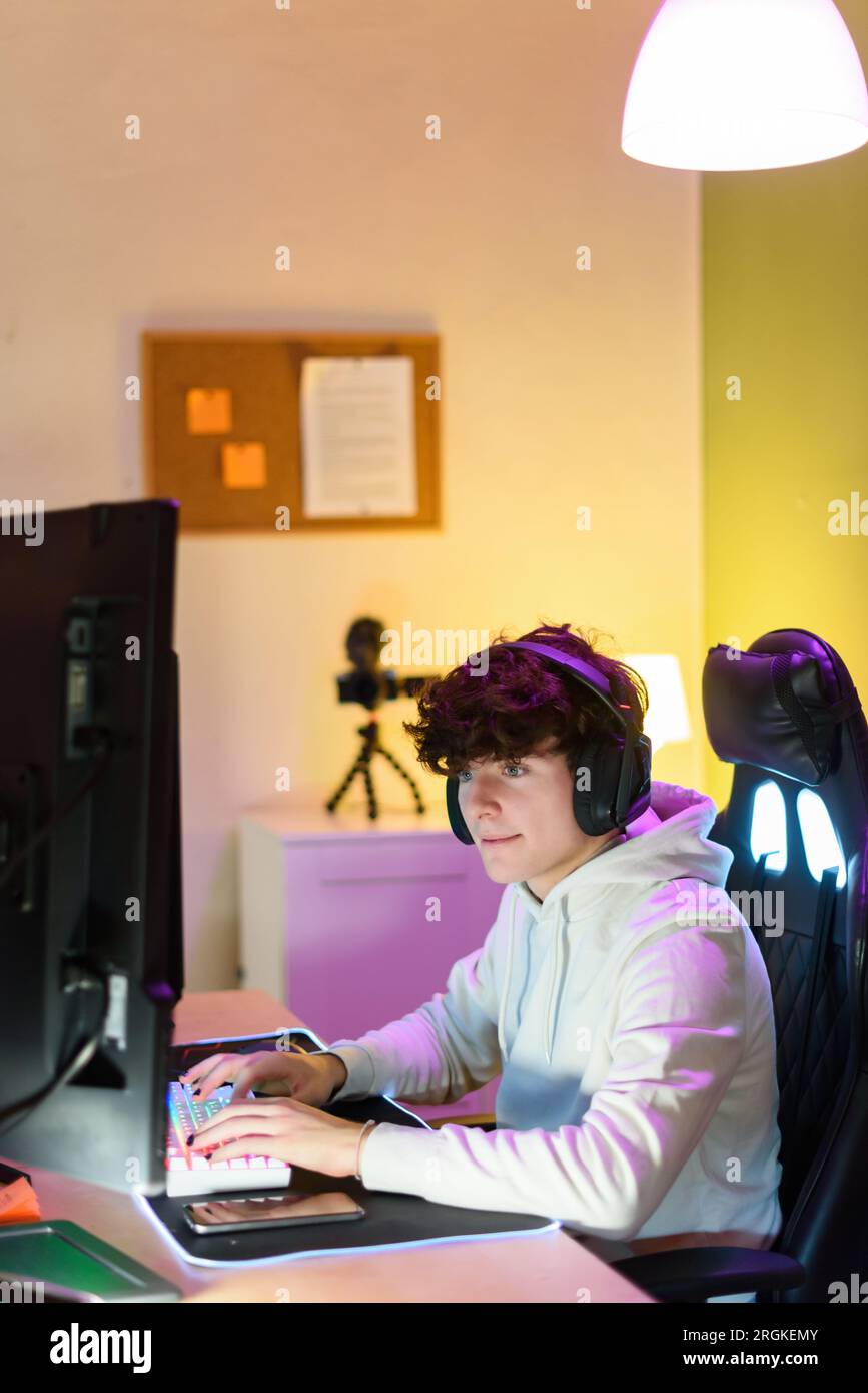 Side view of concentrated young male gamer headphones looking at screen ...